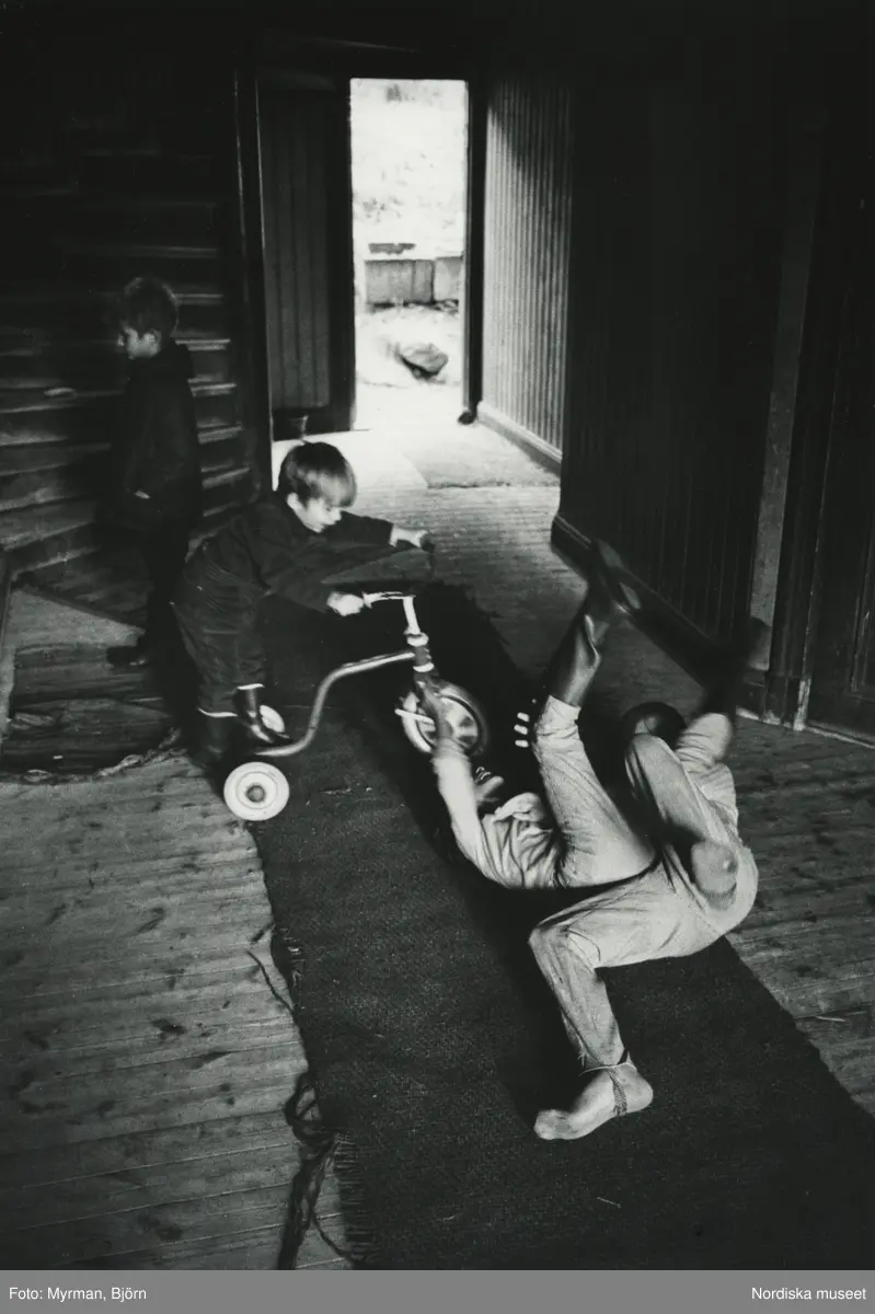 Barn leker och tumlar runt på gångmatta i trapphall. Pojke med ...