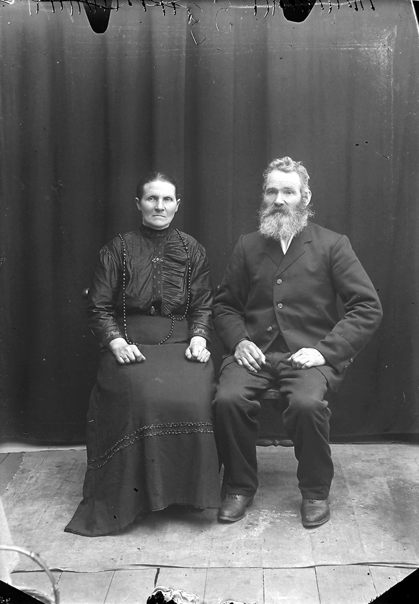 Portrett. Par i 70-80-åra. Begge sitter. Mannen har skjegg. Bildet er ...