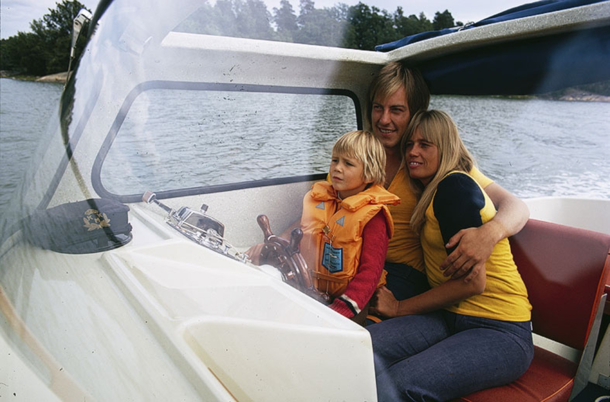 Man med två barn vid styrplatsen på Albin 21. Marknadsföringsbild ...