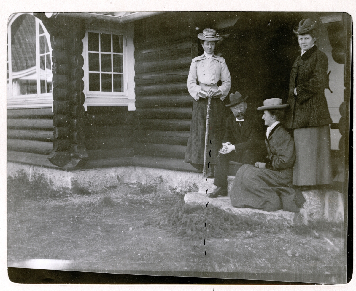 Tre kvinner og en mann ved inngangen til Egeberg-familiens jakthytte ...