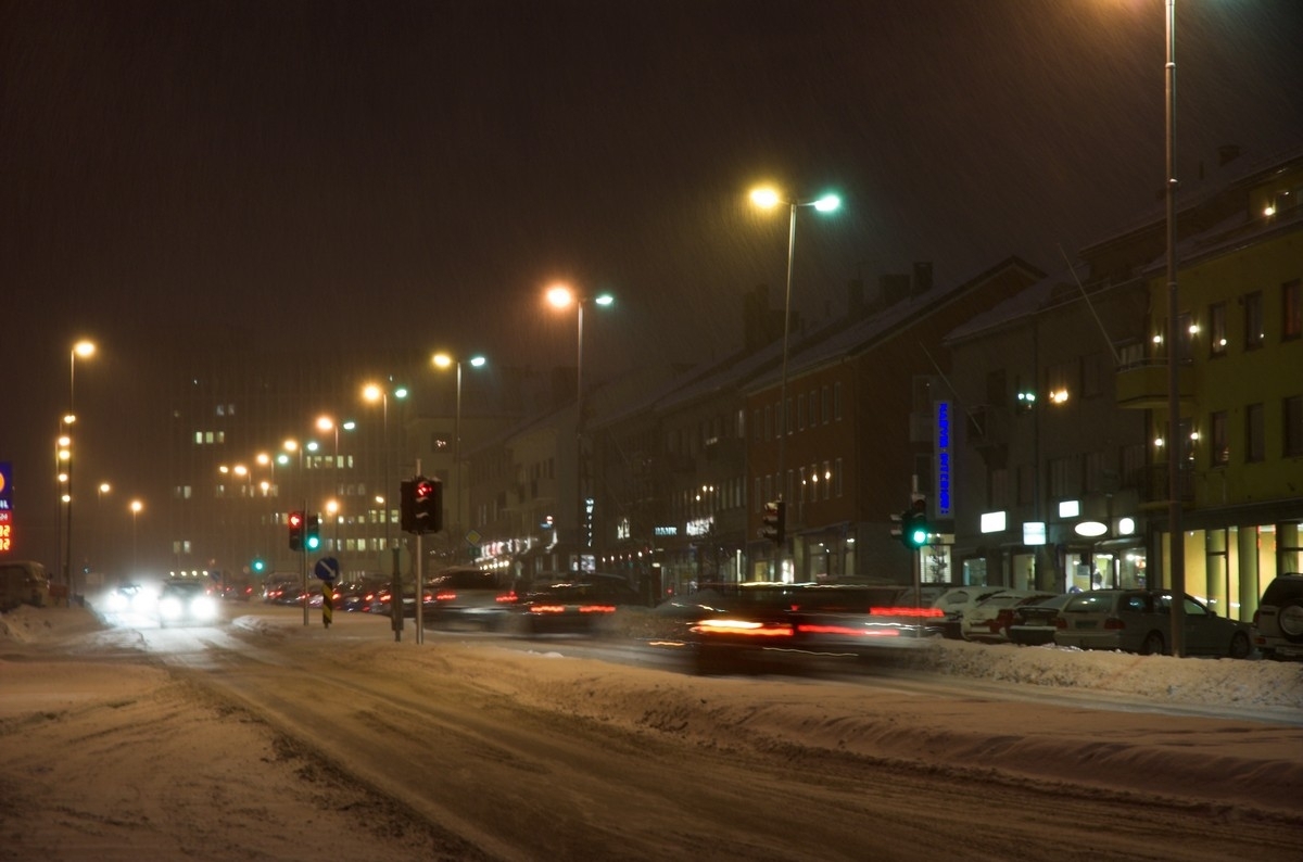 E6, narvik sentrum sør. Snø på bakken og i lufta. Biler med lys ...
