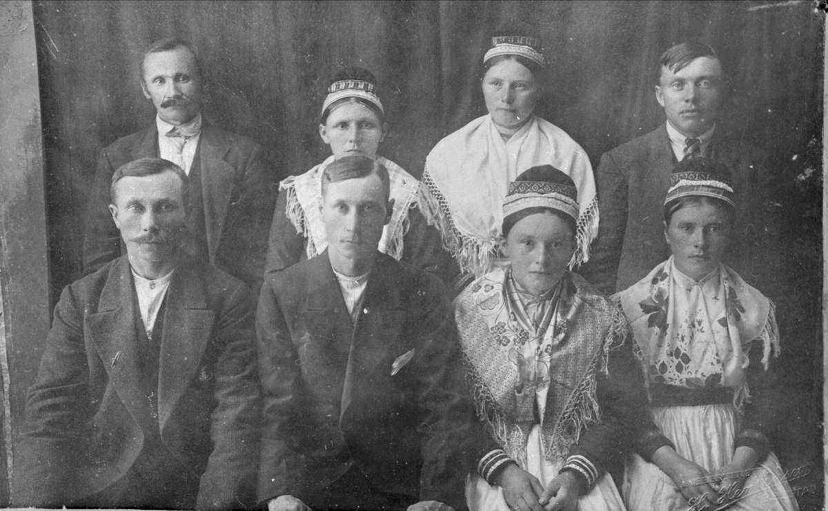 Studioportrett av fire kvinner i samedrakt og fire menn i dress. - Sør ...