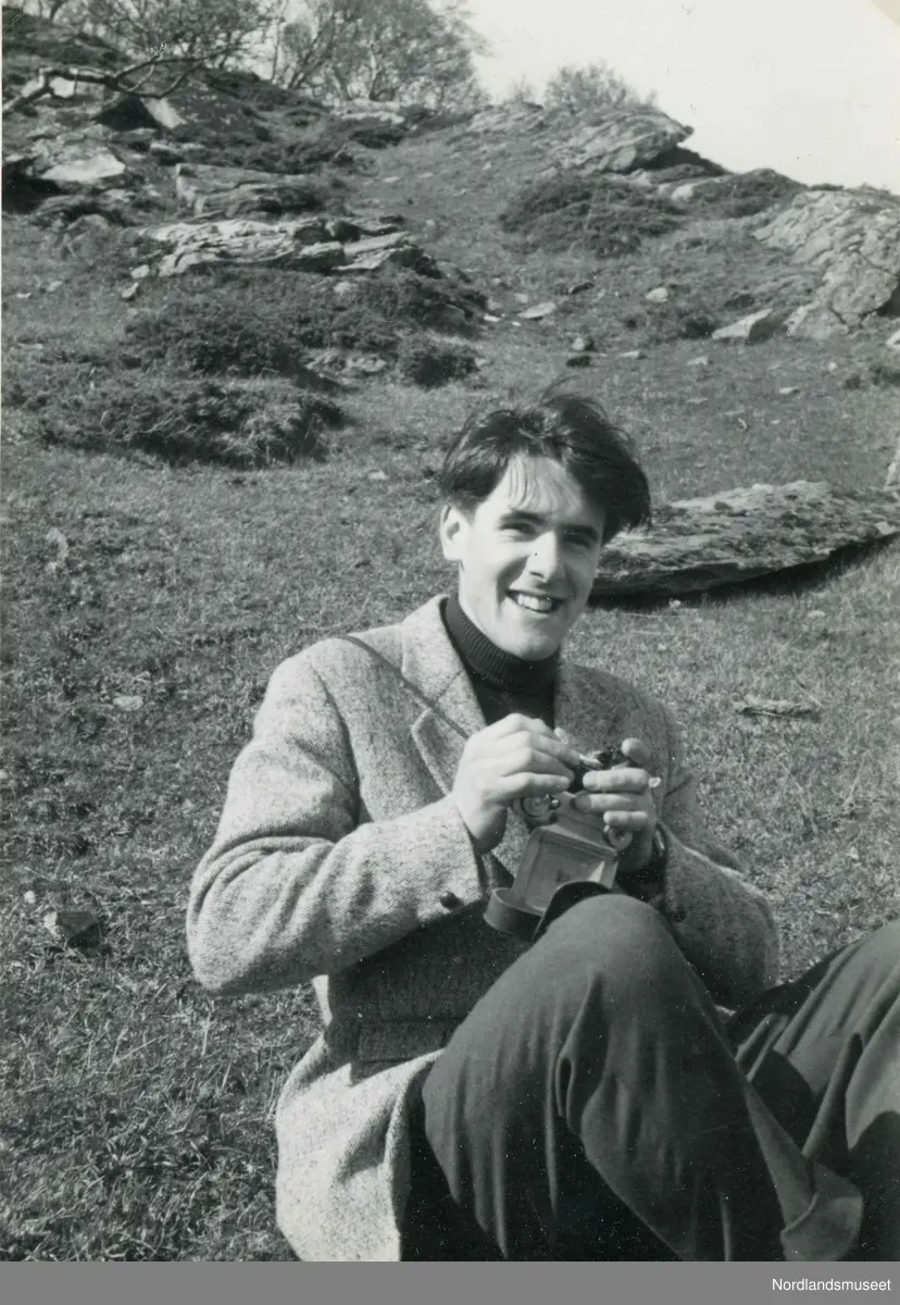 Ung mann som sitter i ei bakkeskråning. John Svensen (f. 1934) fra ...