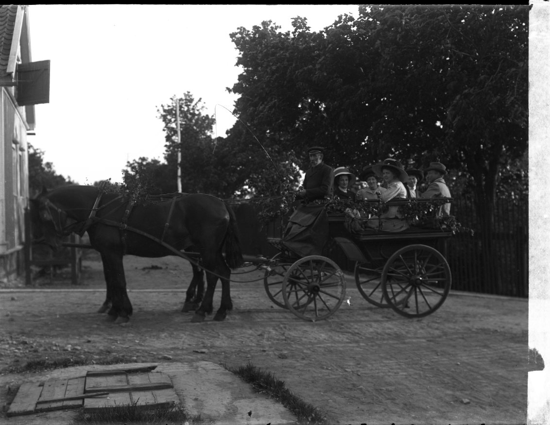 Fyra kvinnor och en man i åkvagn. En kusk på kuskbocken med en piska i ...